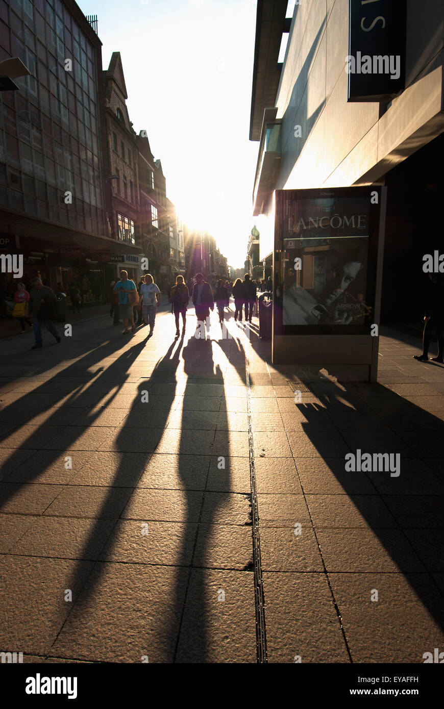 Shadows of pedestrians walking down the walkway between buildings with ...