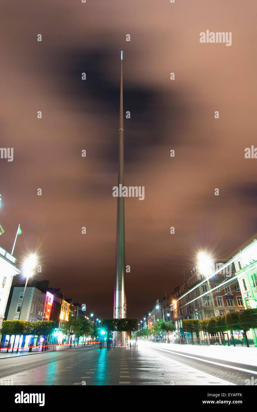 Lights illuminate buildings along a street at nighttime and the Spire ...