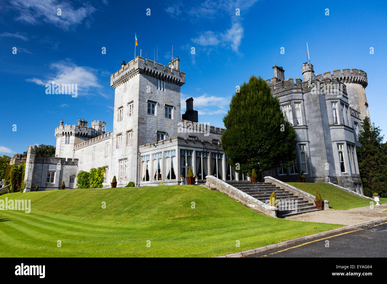 Stone castle on manicured grassy hillside with blue sky and clouds ...