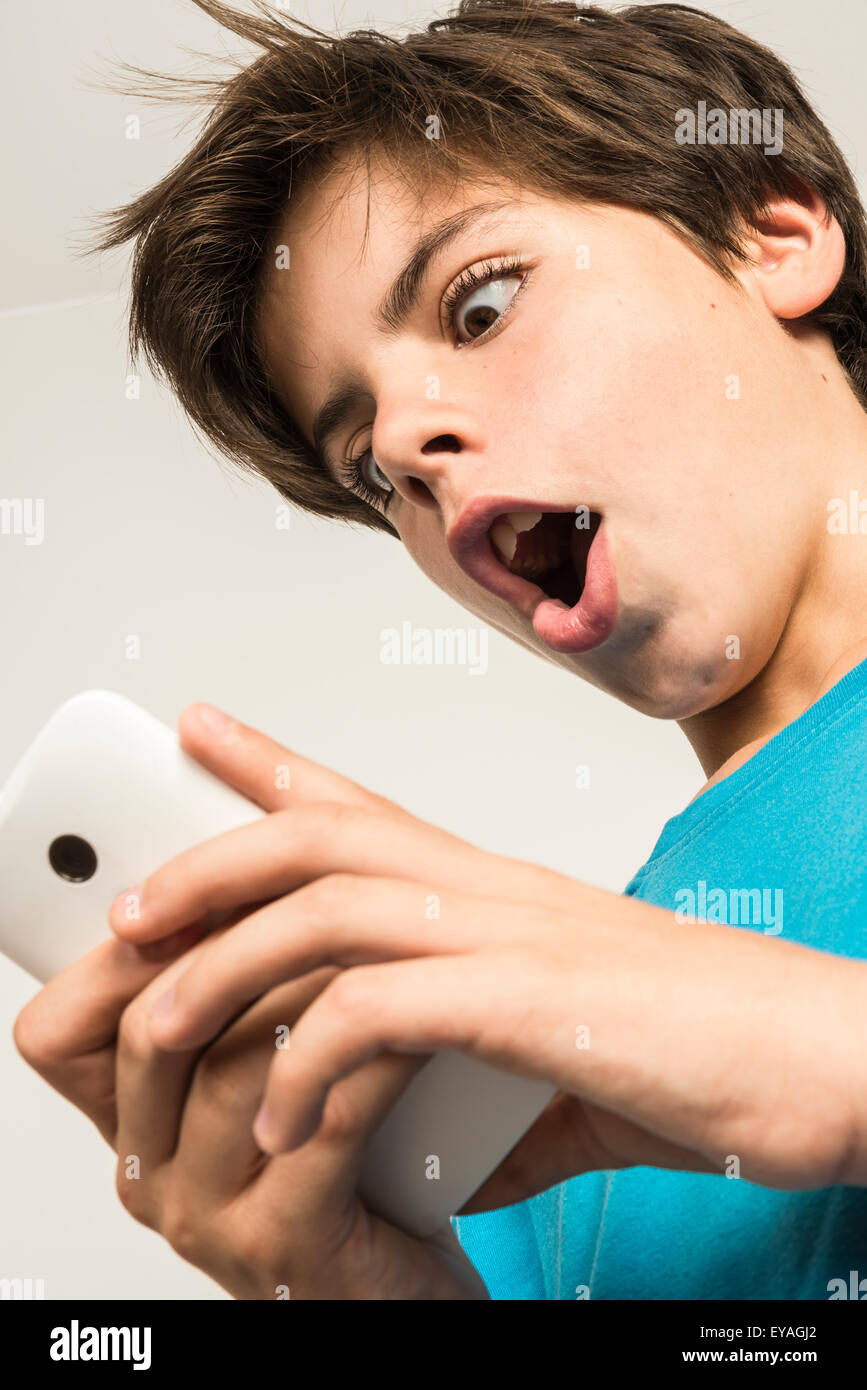 Boy touching a mobile phone with a look of surprise isolated on white ...