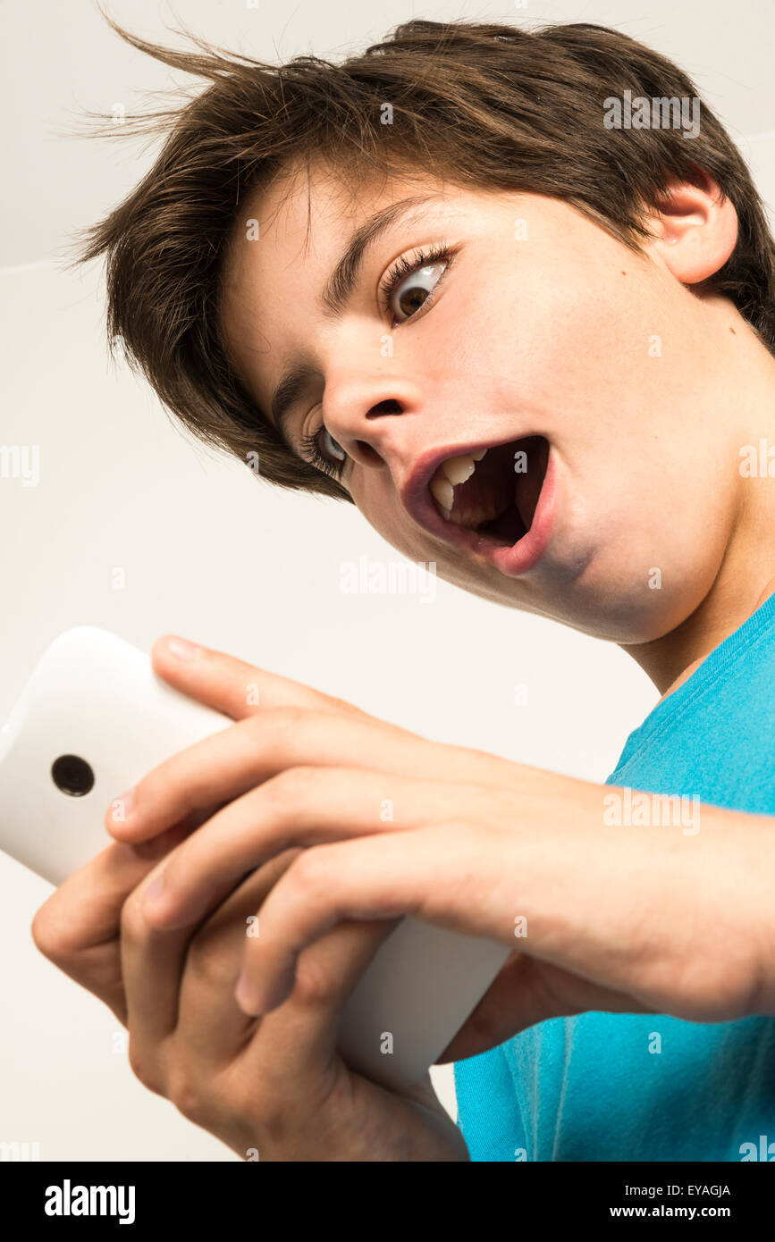 Boy touching a mobile phone with a look of surprise isolated on white ...