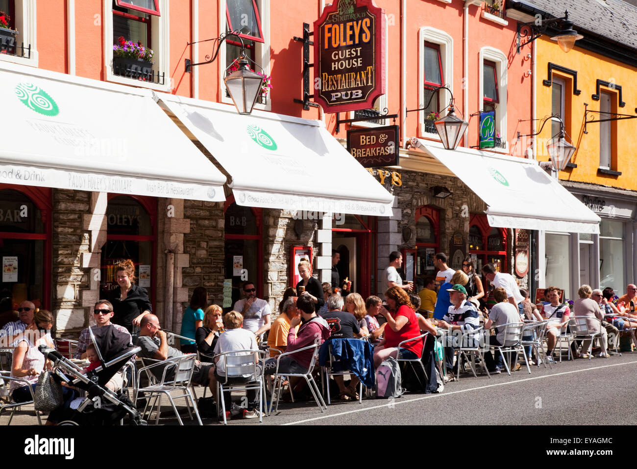 Busy patios outside restaurants along the street; Kenmare, County Kerry ...