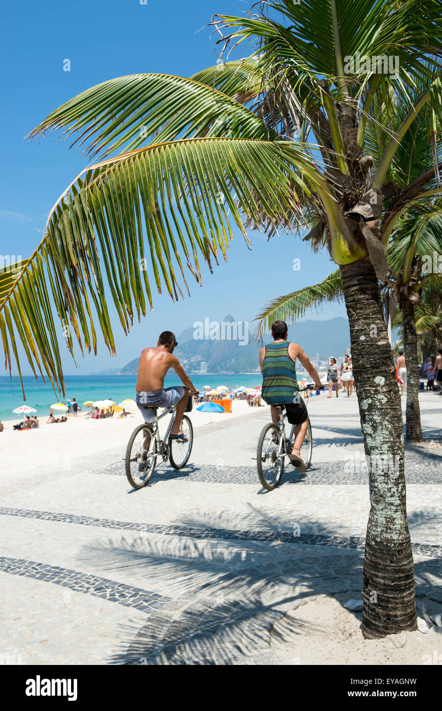 Pair of Brazilians riding bicycles along the boardwalk at Arpoador ...