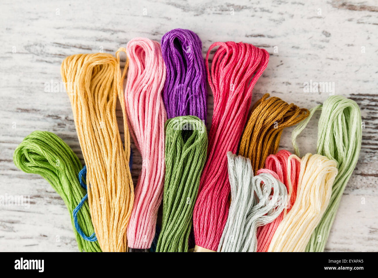 Threads for embroidery from different colors on white wooden background ...