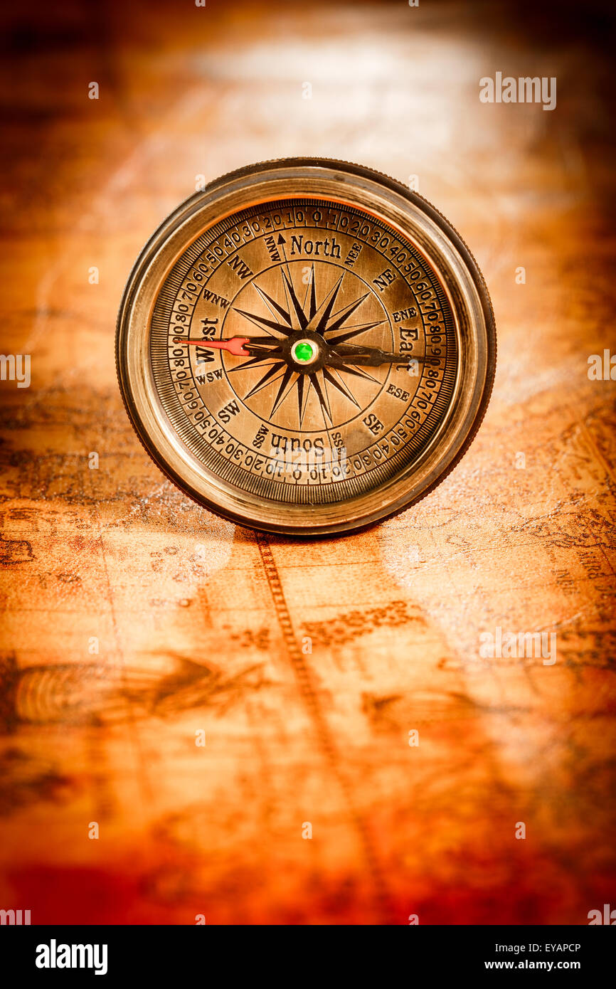 Vintage still life. Vintage compass lies on an ancient world map in ...