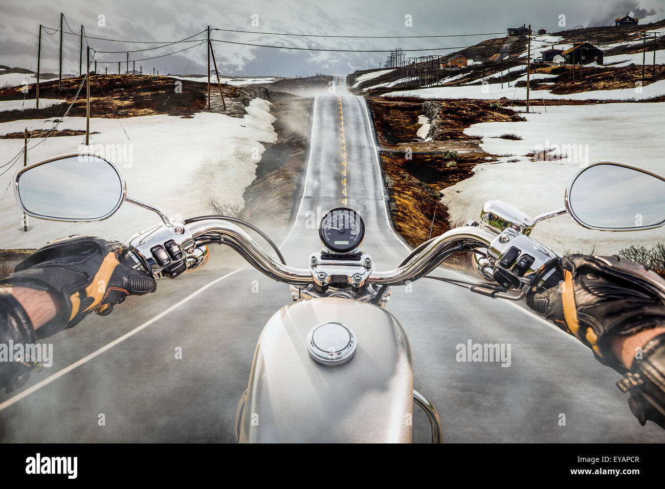 Biker rides a motorcycle on a slippery road through a mountain pass in ...
