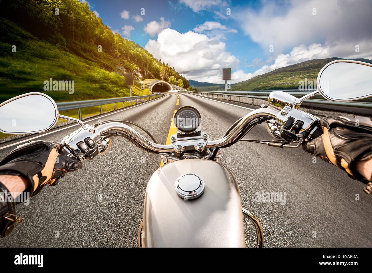 Biker driving a motorcycle rides along the asphalt road. First-person ...