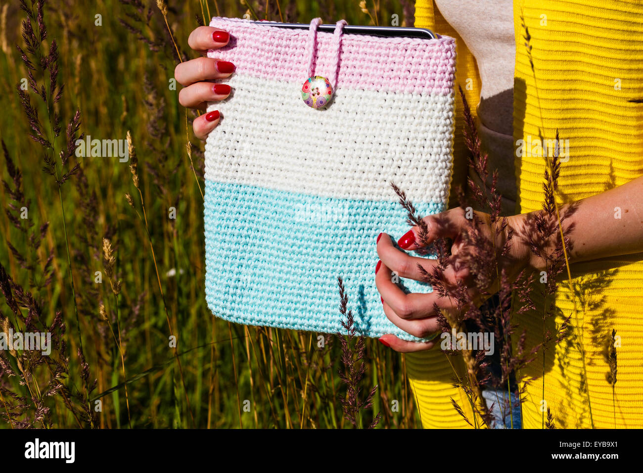 yarn girl with tablet computer in a knitted cover on wild meadow with ...
