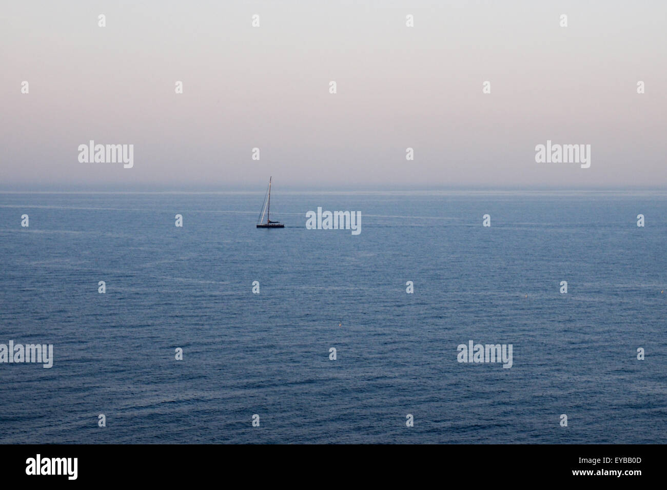 Sailing boat with sails down on calm waters Stock Photo - Alamy