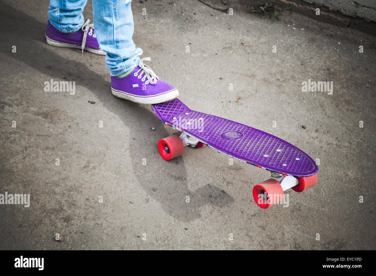 Young skateboarder feet in gumshoes and jeans standing on his skate ...