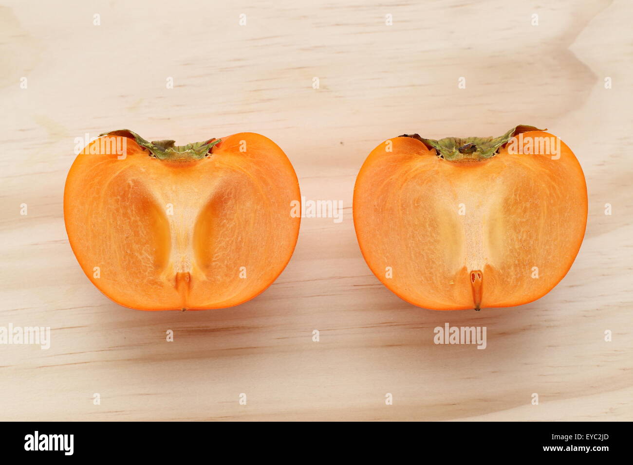 One fresh orange colour persimmons cut in half on a wooden board Stock ...