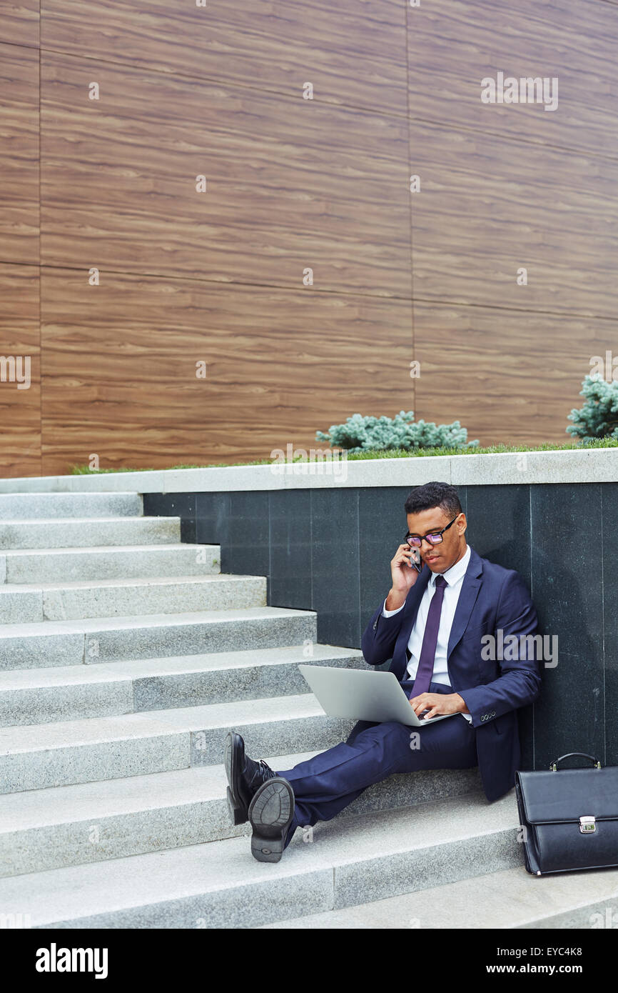 Modern employee using laptop and cellphone in urban environment Stock ...