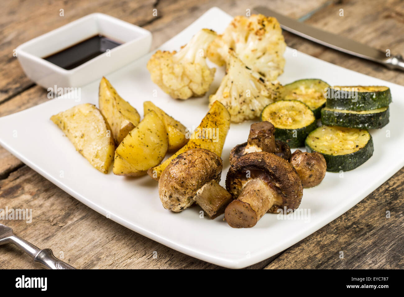 Roasted vegetables with sauce served on wooden table. Vegetarian menu ...