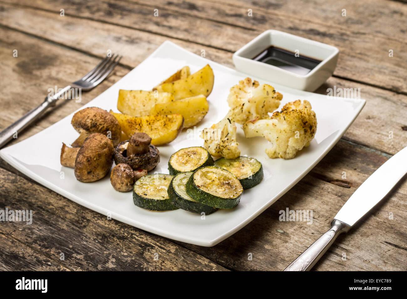 Roasted vegetables with sauce served on wooden table. Vegetarian menu ...