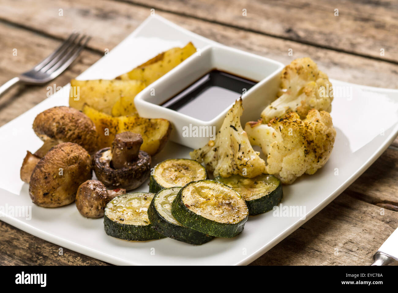 Roasted vegetables with sauce served on wooden table. Vegetarian menu ...