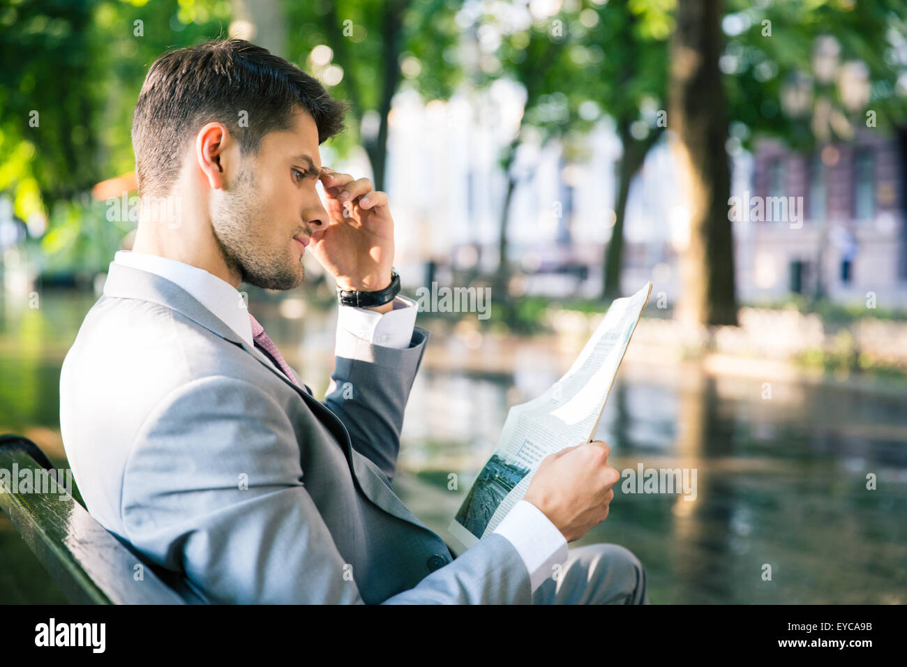 Thoughtful businessman reading newspaper outdoors Stock Photo - Alamy