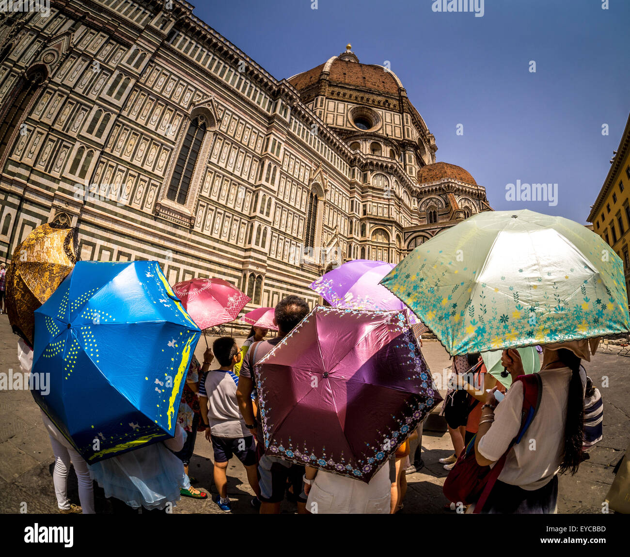 Tourists using umbrellas to protect themselves from the sun outside ...