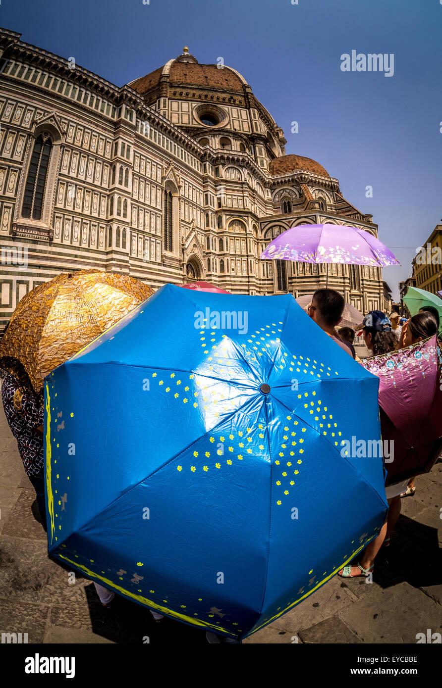 Tourists using umbrellas to protect themselves from the sun outside ...