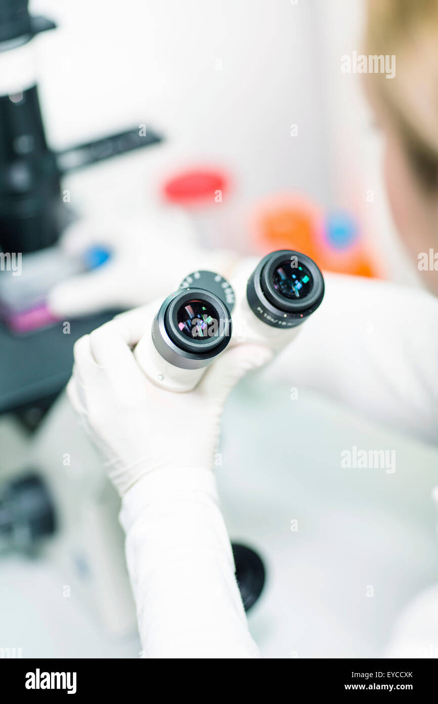 Woman looking through microscope Stock Photo - Alamy