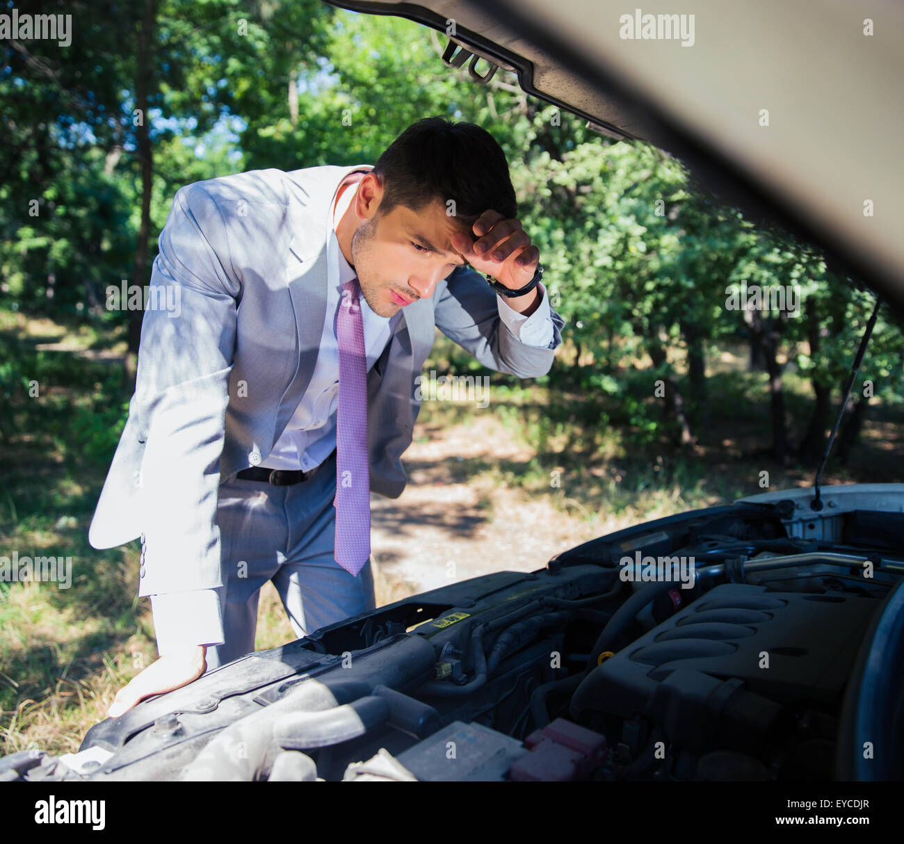 Businessman looking under the hood of breakdown car in forest Stock ...