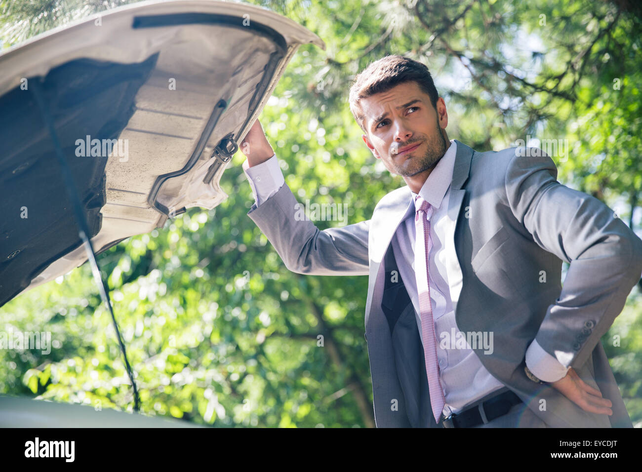 Pensive man standing near breakdown car and looking away Stock Photo ...