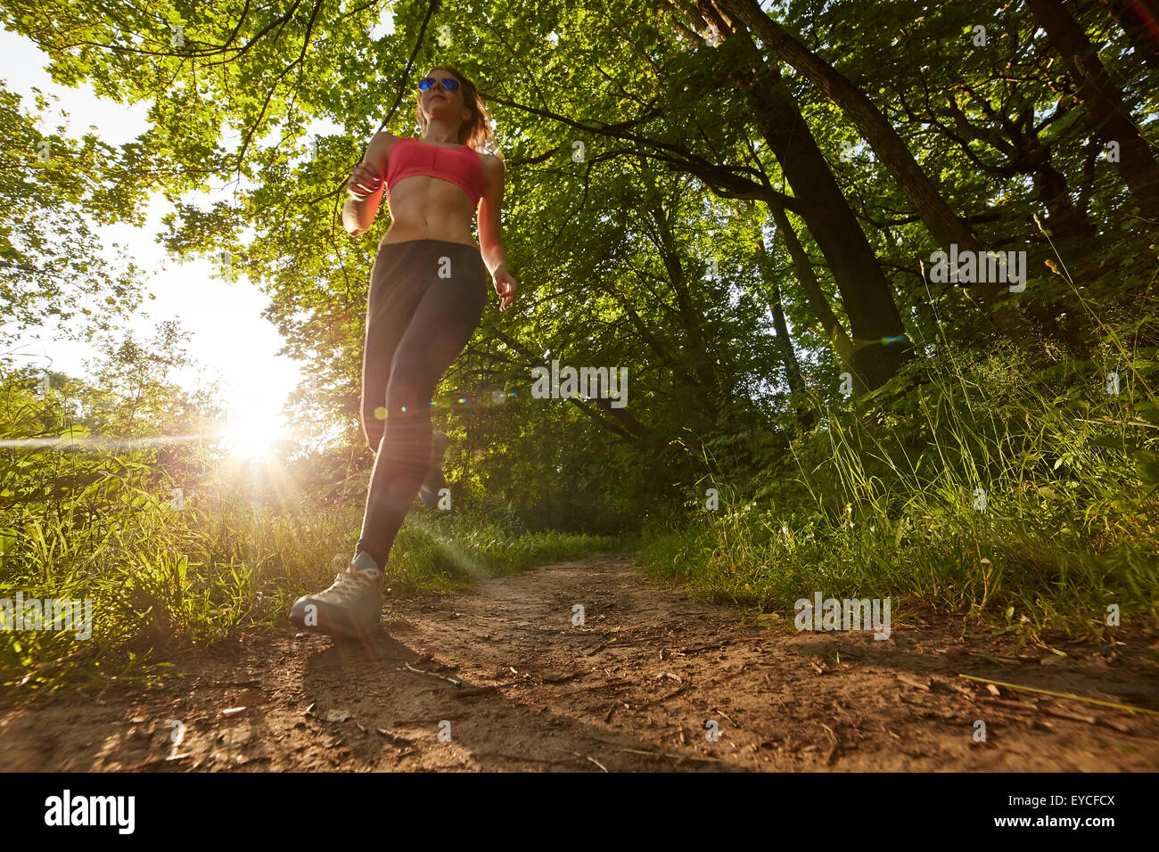 muscular woman running in sunny wood, image with motion blurred effect ...