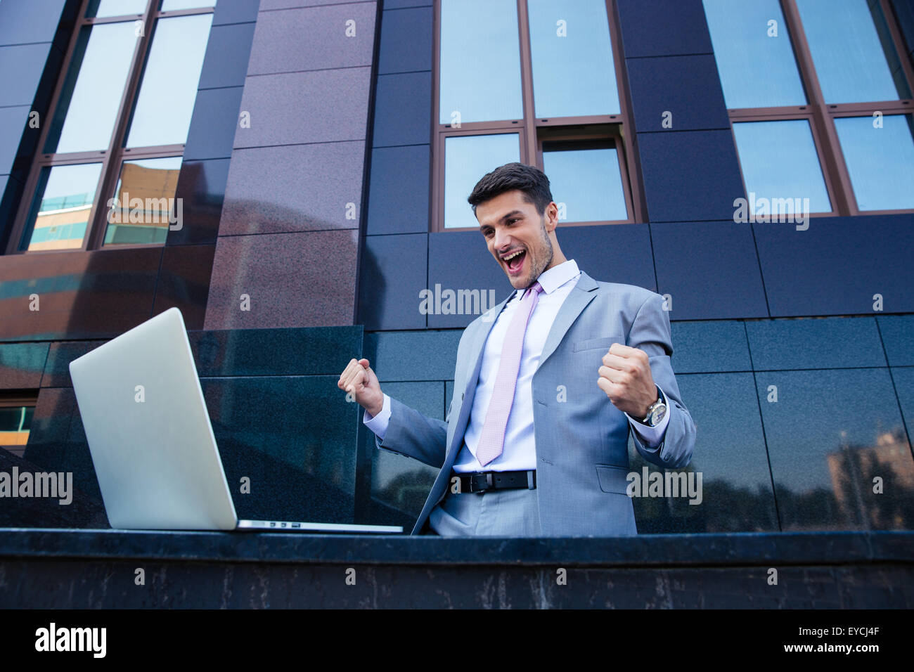 Happy businessman looking at laptop and celebrating his success ...
