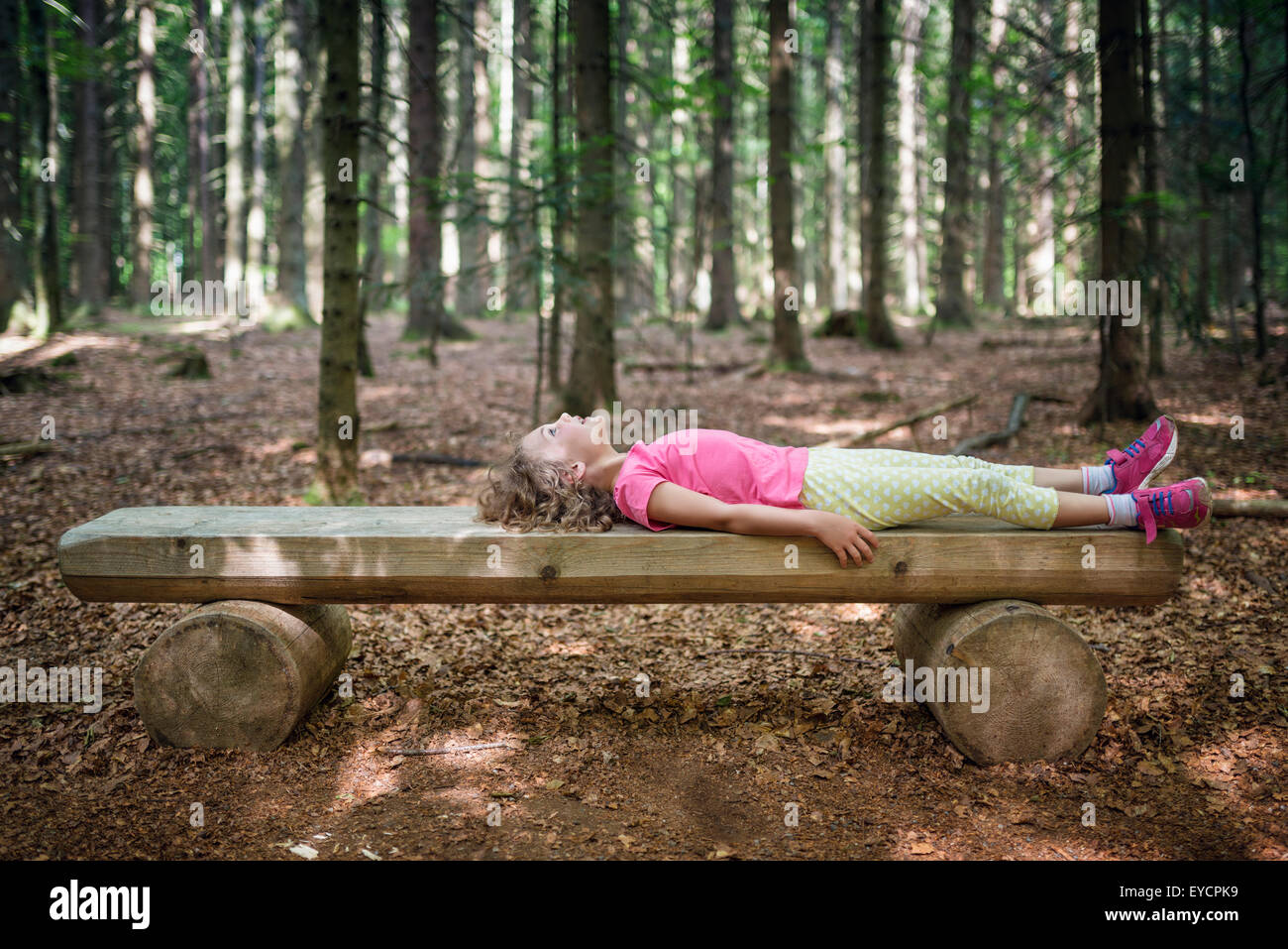 Girl lying on wooden bench in forest looking up Stock Photo - Alamy