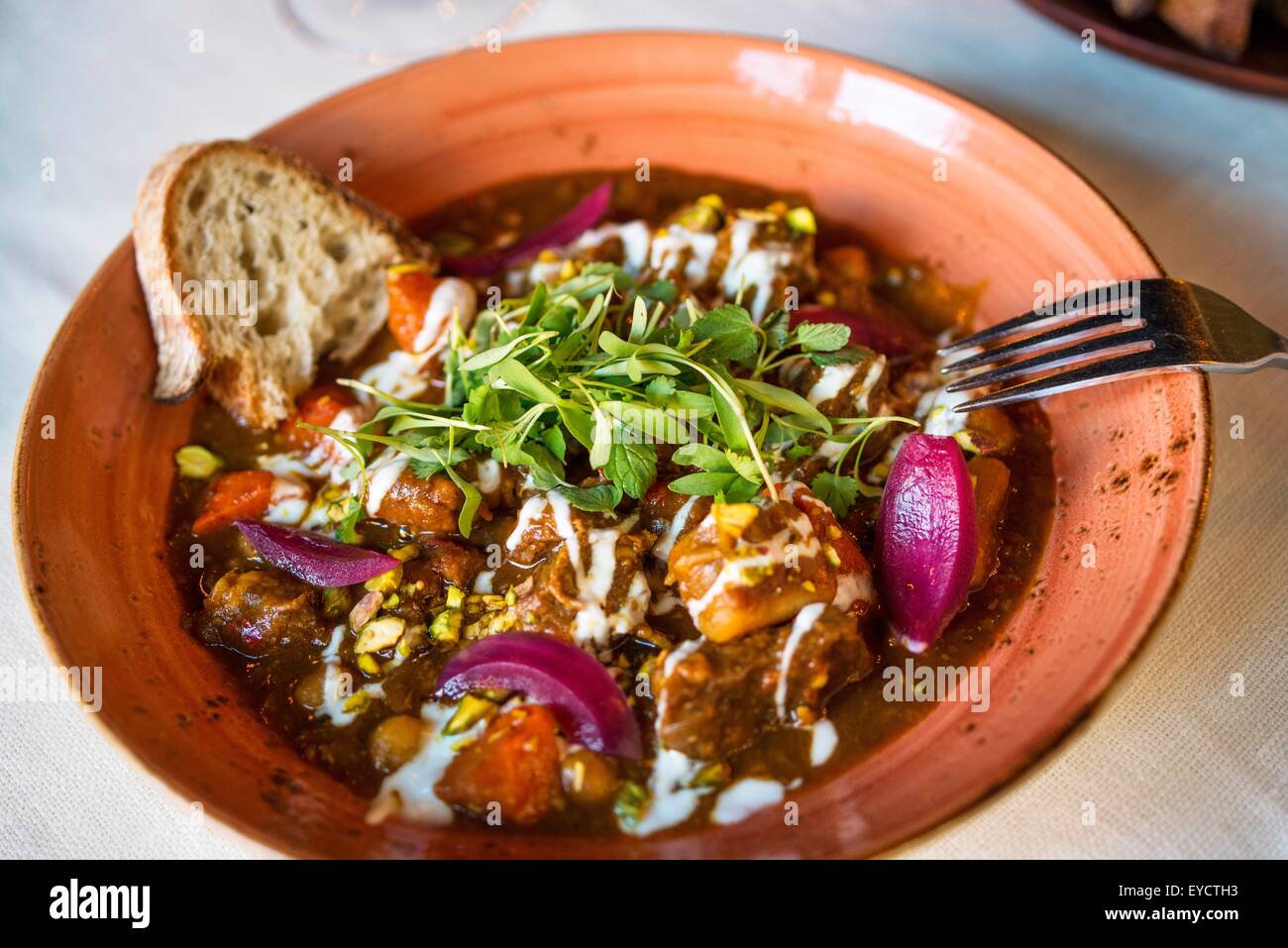 Bowl of stew with herb garnish on restaurant table Stock Photo - Alamy