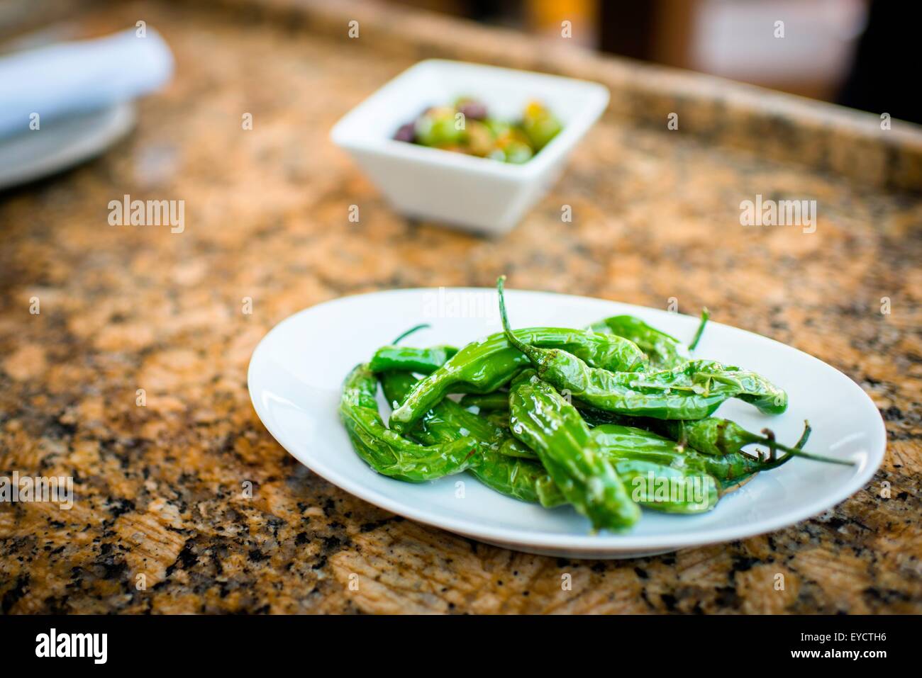 Plate with green chilli appetizer on restaurant table Stock Photo - Alamy