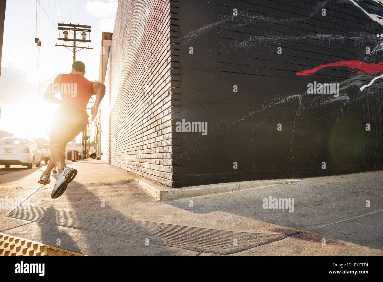 Rear view of male runner running on sidewalk Stock Photo - Alamy