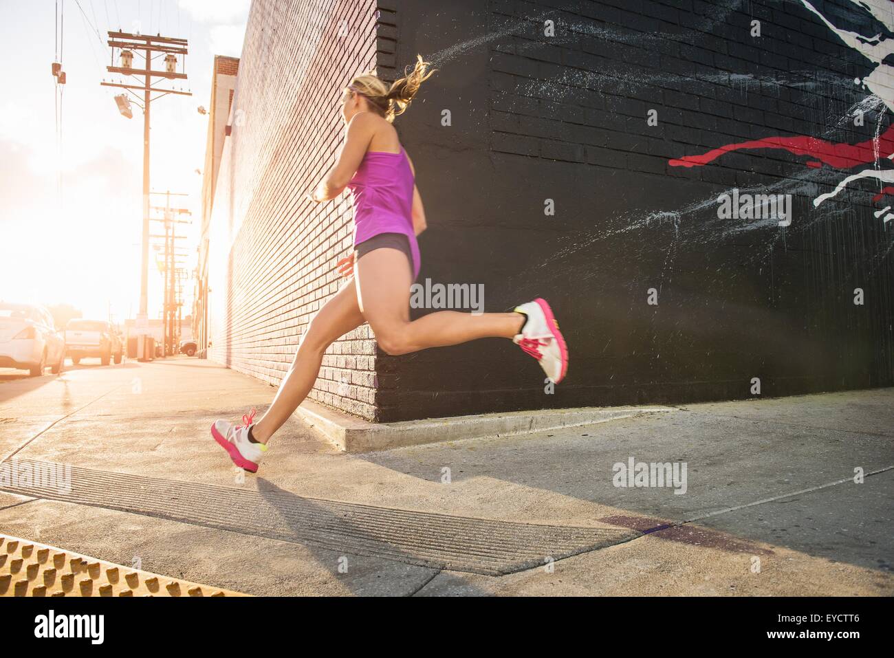 Female runner running along sidewalk Stock Photo - Alamy