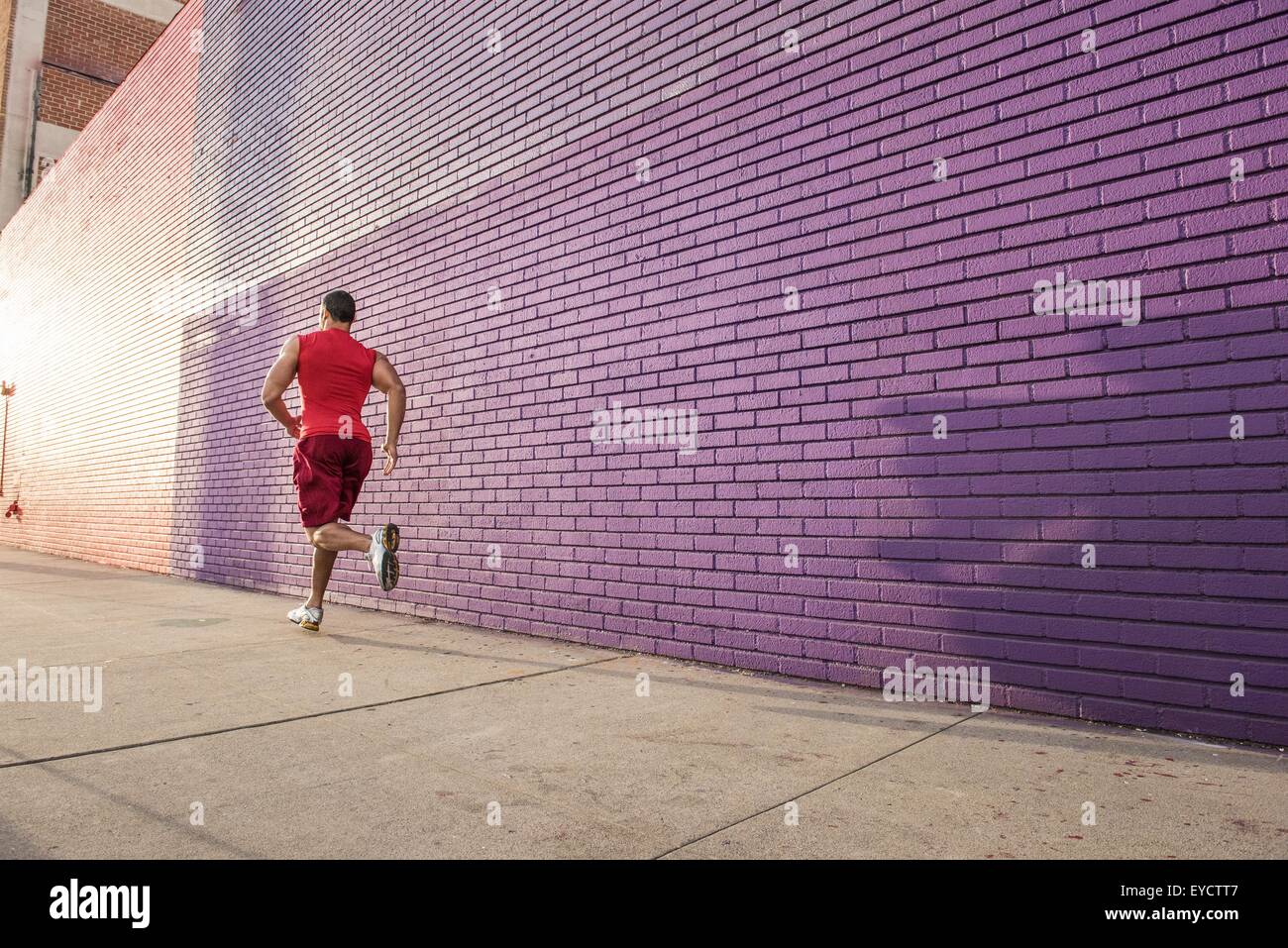 Rear view of male runner running along sidewalk Stock Photo - Alamy
