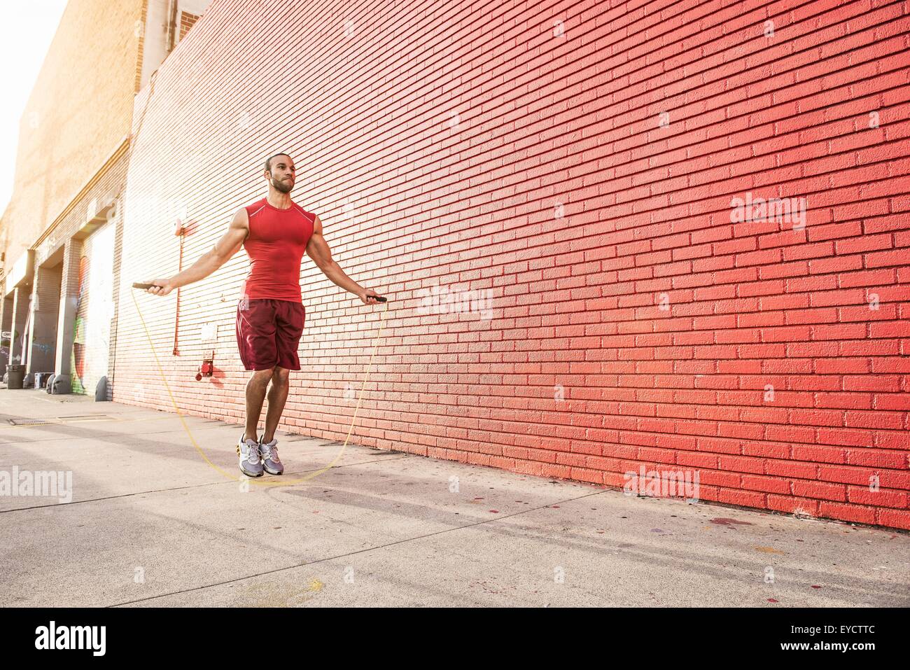 Male runner skipping on sidewalk Stock Photo - Alamy