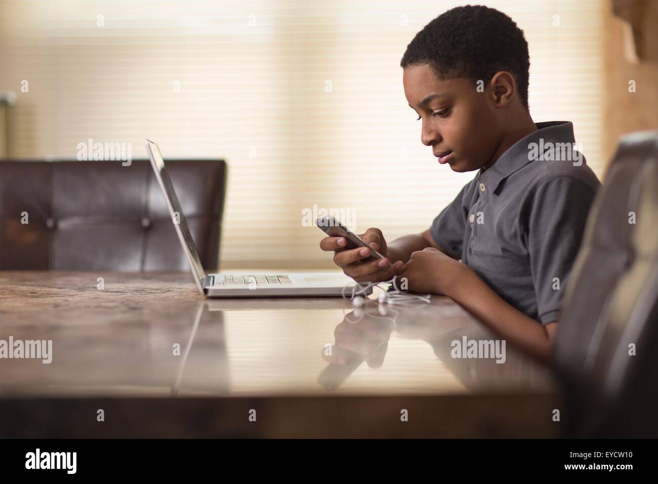 Teenage boy at dining table reading smartphone texts Stock Photo - Alamy