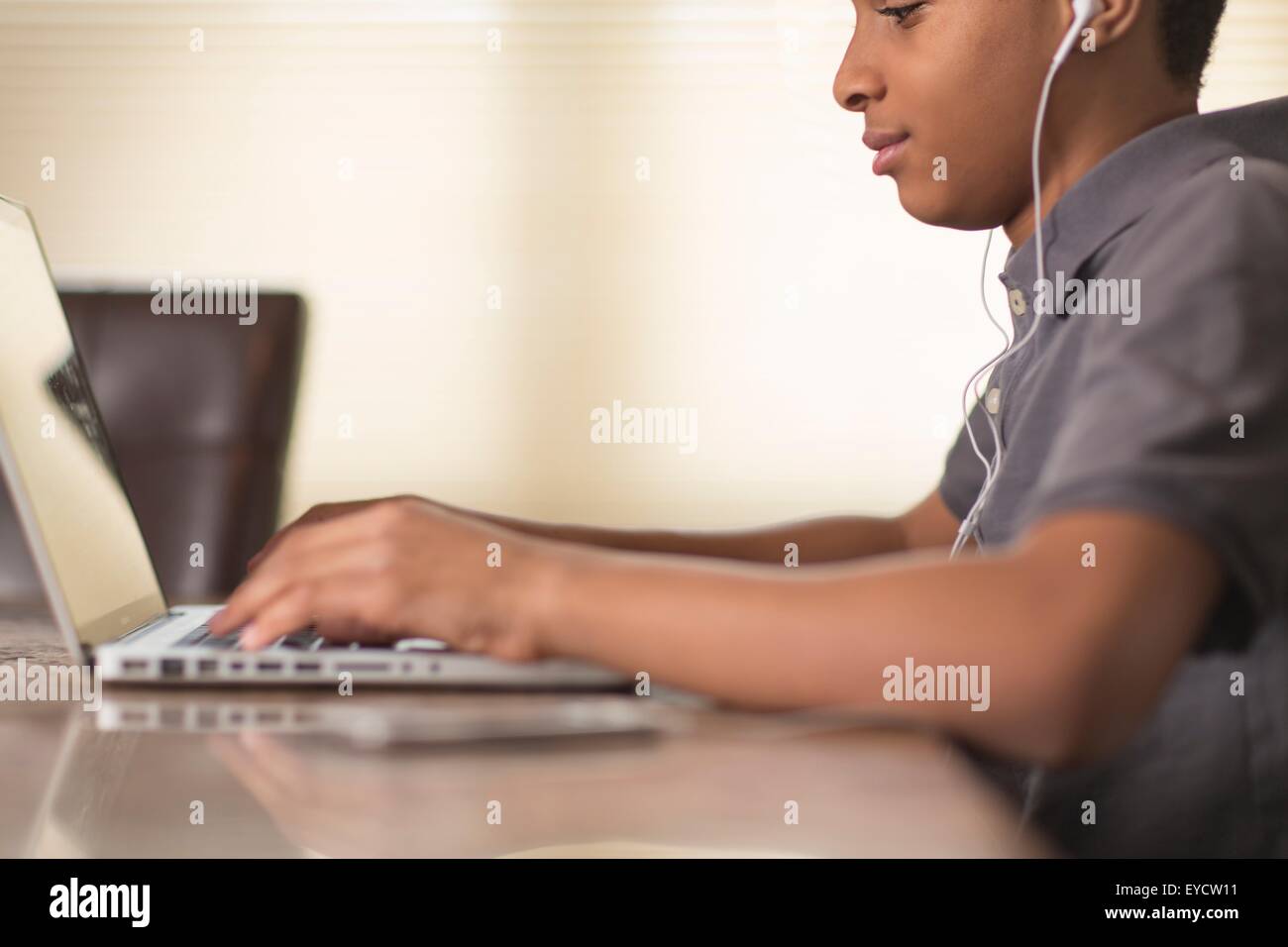 Cropped shot of teenage boy at dining table typing on laptop Stock ...