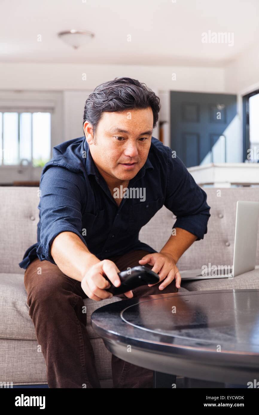 Mature man on sofa reaching for remote control Stock Photo - Alamy