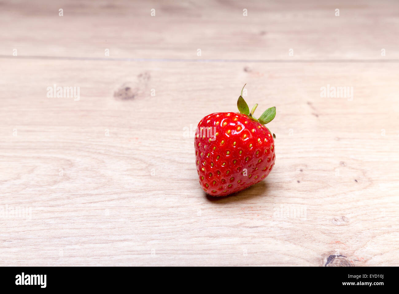 single fresh strawberry on a wood table Stock Photo - Alamy