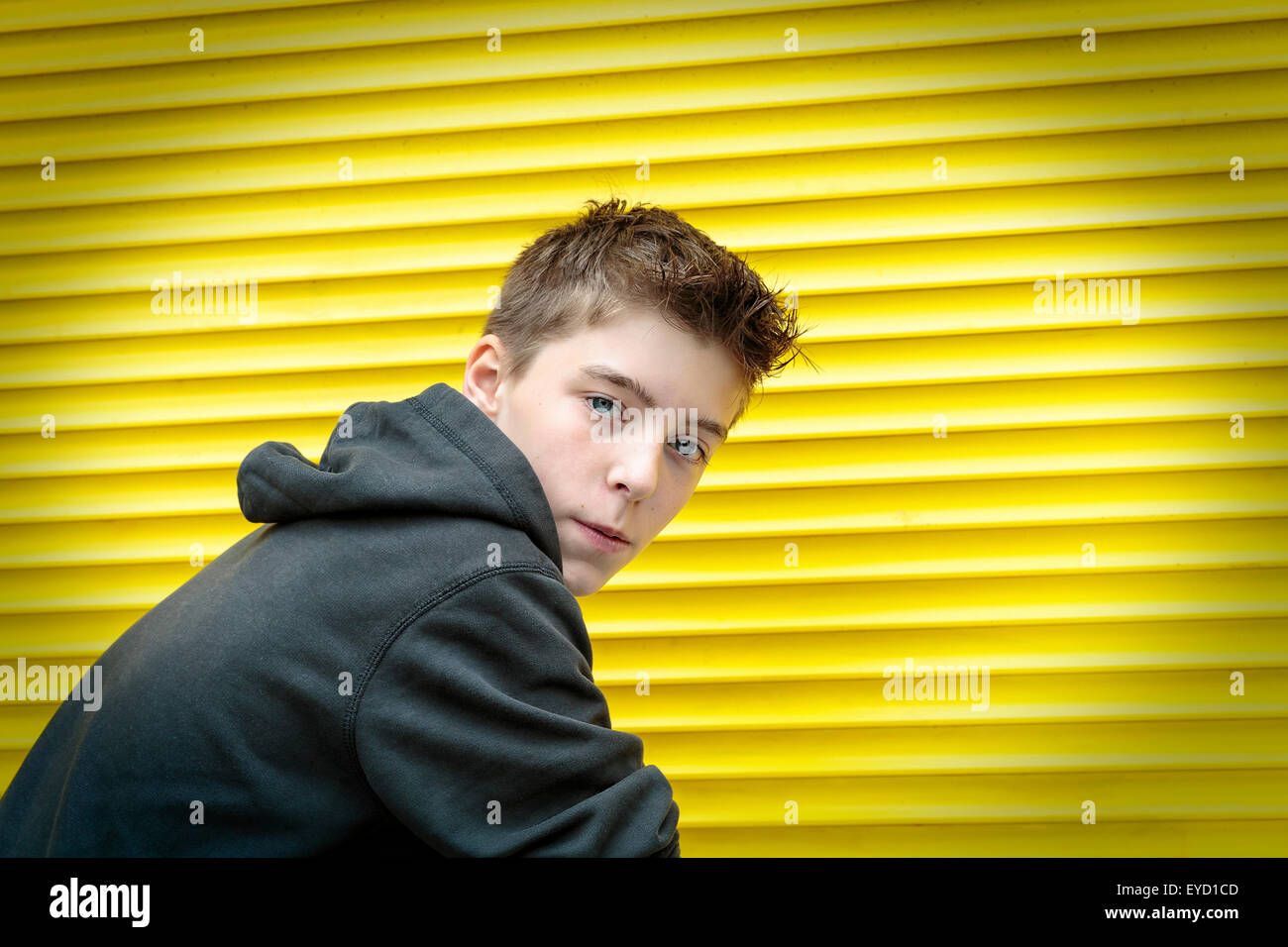 portrait of a male teenager with yellow rolling shutter in background ...