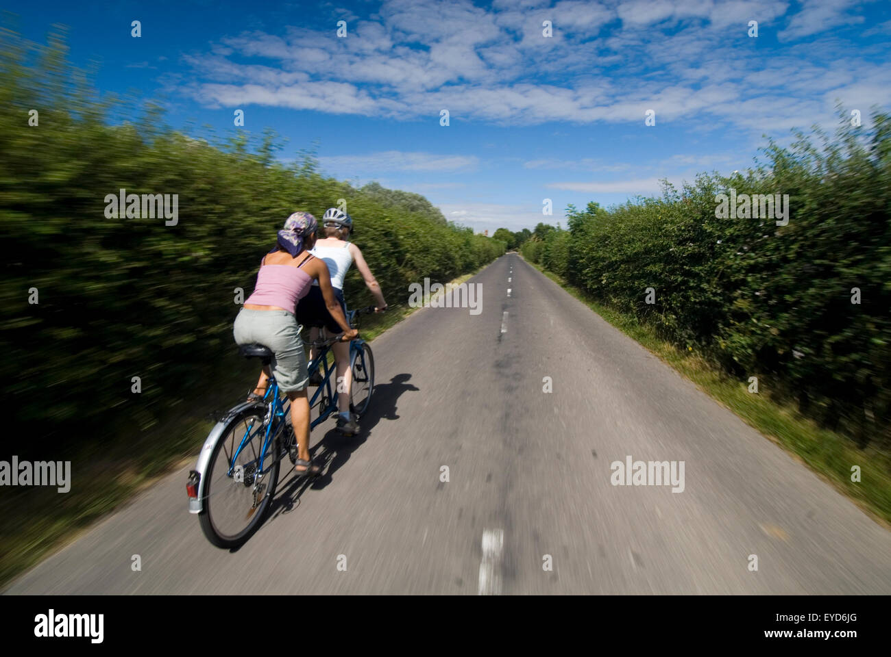 Two Women Cycling On Tandem Down Road In The Countryside; Kent England ...