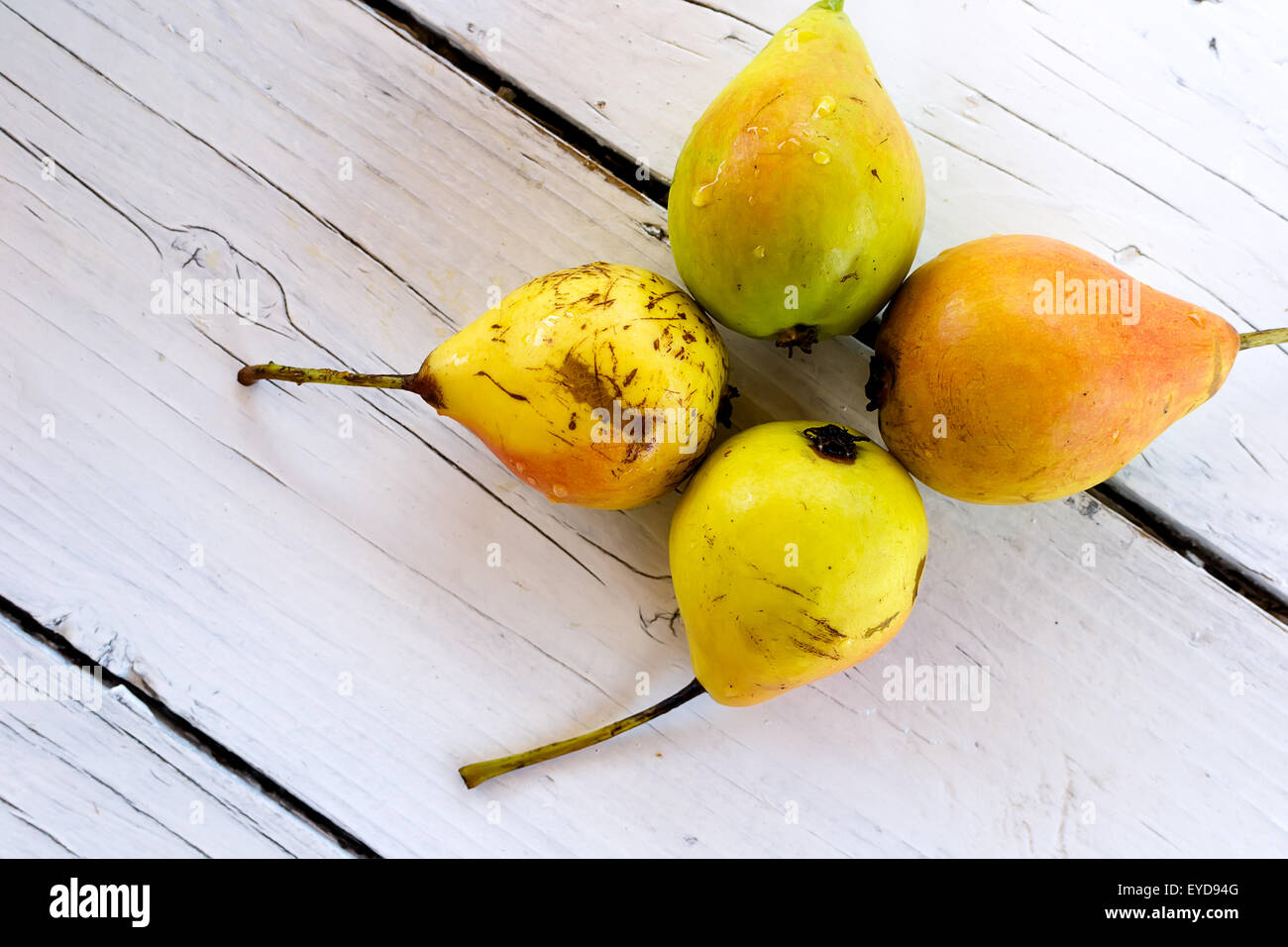 Four fresh and ripe pears on white wooden table Stock Photo - Alamy