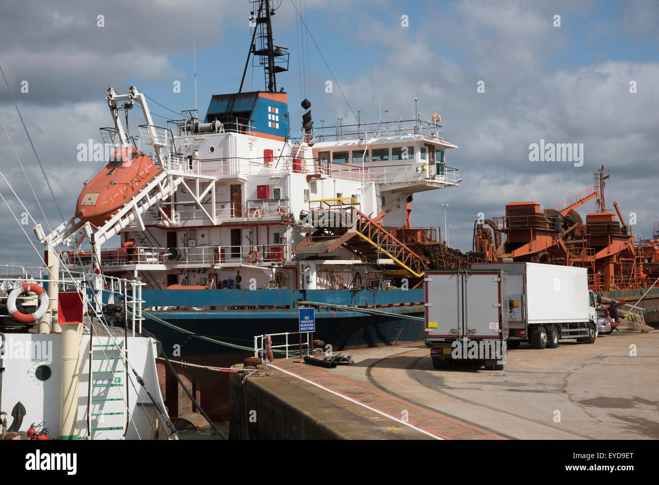 Ship berthed alongside a quay with ship supplies delivery lorries ...