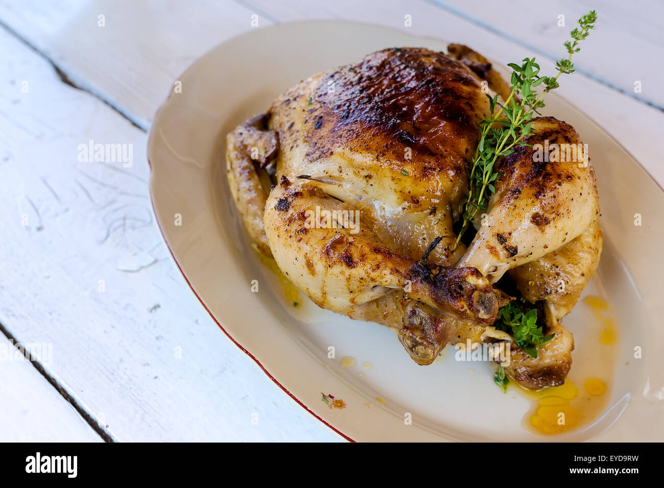 Whole roast chicken in a white plate on a white wooden table Stock ...