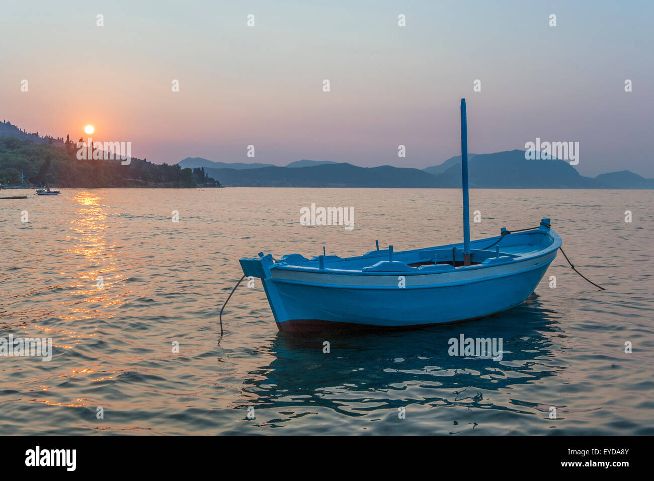 A small Greek fishing boat in a calm sea at sunset in the Greek Islands ...