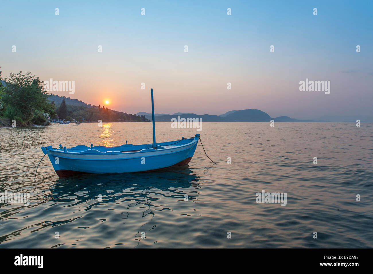 A small Greek fishing boat in a calm sea at sunset in the Greek Islands ...