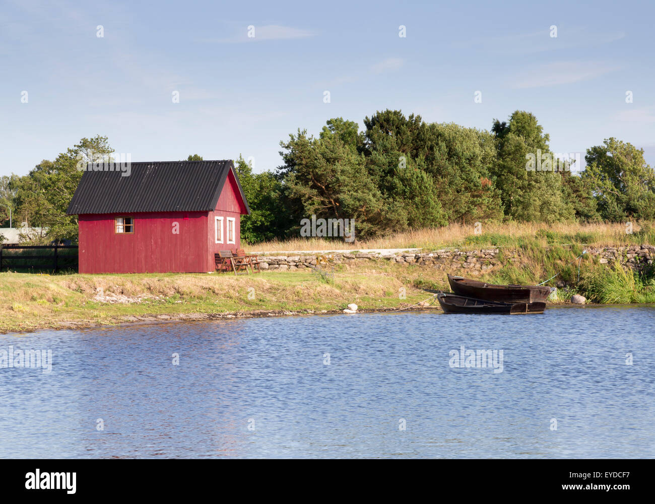 Red House by Rowing Boats and water with blue sky Stock Photo - Alamy