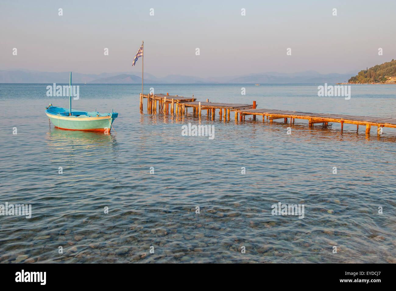 A small Greek fishing boat by a jetty with a Greek flag in the Greek ...