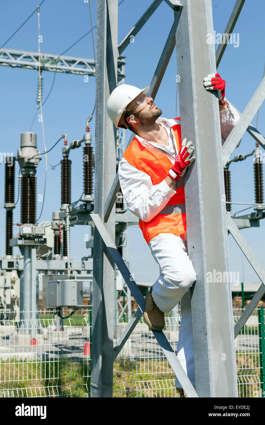 Engineer climbing electricity pylon Stock Photo - Alamy