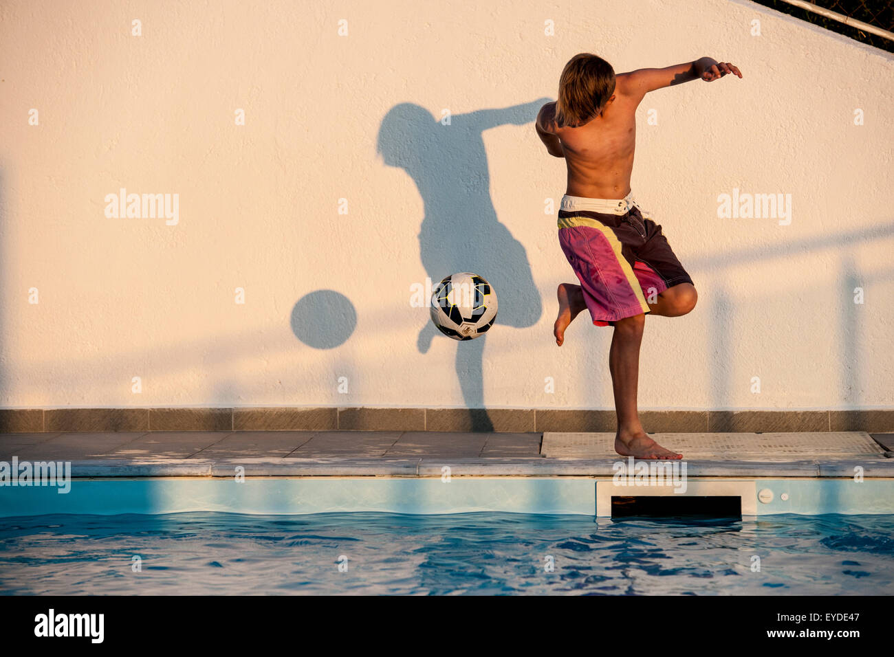 A boy playing football on holiday by a swimming pool Stock Photo - Alamy