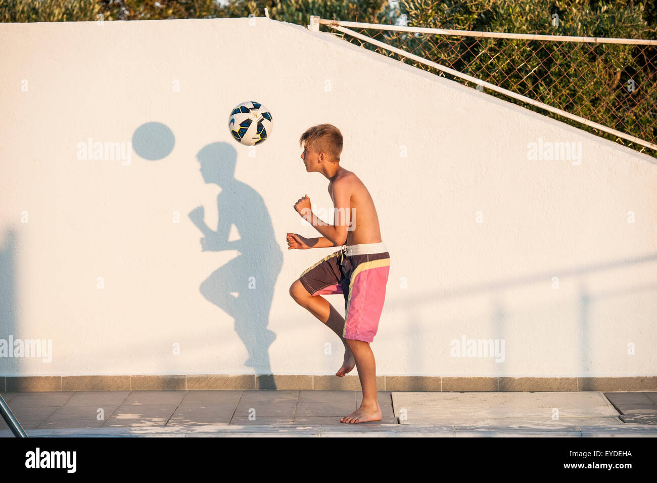 A boy playing football on holiday by a swimming pool Stock Photo - Alamy